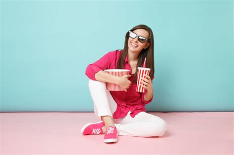 전체 길이 세로 재미 여자 장미 셔츠에서 흰색 바지 밝은 핑크 블루 파스텔 벽 배경 스튜디오에 고립 된 보고 영화 필름을 바닥에 앉아 패션 라이프 스타일 개념입니다 복사