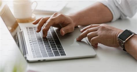 커피 컵과 사무용품이 있는 간단한 작업 공간에서 노트북으로 입력하는 동안 작업을 수행하는 사업가의 측면 모습 사진 Unsplash의 태국 이미지