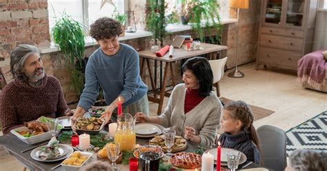 젊은 쾌활한 갈색 머리 여자는 크리스마스 날 가족 저녁 식사 중에 구운 감자를 축제 테이블에 놓고 남편을 바라보고 있습니다 사진 Unsplash의 식탁 이미지