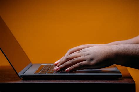 복사 공간이있는 노란색 겨자 색 스튜디오 배경 앞에서 극적인 조명 아래 노트북 컴퓨터에 타이핑 젊은 전문 아프리카 계 미국인 여성의 손 노트북에 대한 스톡 사진 및 기타