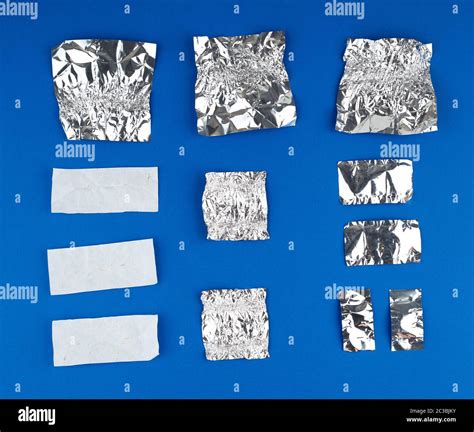 Various Crumpled White Paper And Foil Used Candy Wrappers On A Blue Background Top View Stock