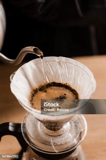 깔때기에 분쇄 커피가 있는 필터를 클로즈업하여 초점을 맞춥니다 드립 필터 커피 추출 필터에 포함된 볶은 커피 원두와 분쇄 커피 원두 위에 물을 붓는 다른 방법을 붓습니다