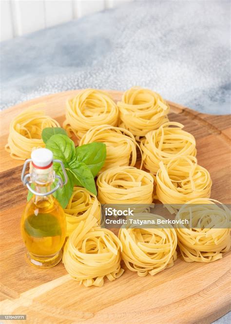 조리되지 않은 드라이 타글리아텔 파스타 둥지 바질과 올리브 오일이 있는 나무 판에 가정 생활에 대한 스톡 사진 및 기타 이미지 가정 생활 가정 주방 가정의 방