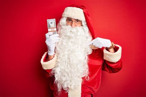 자신에게 손가락을 가리키는 깜짝 얼굴과 고립 된 빨간 배경을 통해 달러를 들고 산타 클로스 의상을 입고 중년 남자 가리키기에 대한 스톡 사진 및 기타 이미지 Istock