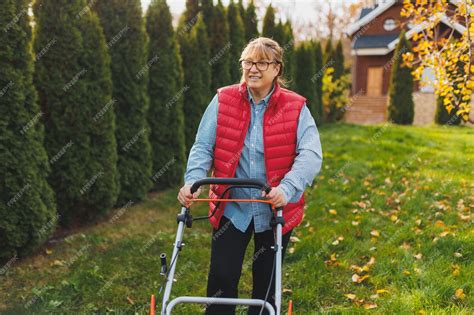 Premium Photo Middle Aged Woman In Red Vest Using Lawn Mower On Backyard Looking At Camera