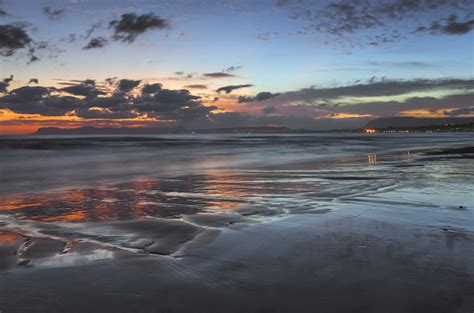 믿을 일출 오렌지 하늘이 반사 되는 바다 해안의 젖은 모래 산 바다와 도시의 아침 풍경 점등 로맨틱 한 휴식 장소 아기아 마리나 비치 크레타 0명에 대한 스톡 사진 및 기타