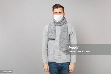 회색 스웨터에 있는 젊은이로 메 마른 얼굴 마스크 서 회색 배경 스튜디오 초상화에 고립 된 스카프 건강 한 라이프 스타일 아픈 아픈 질병 치료 추운 계절 개념 복사 공간을