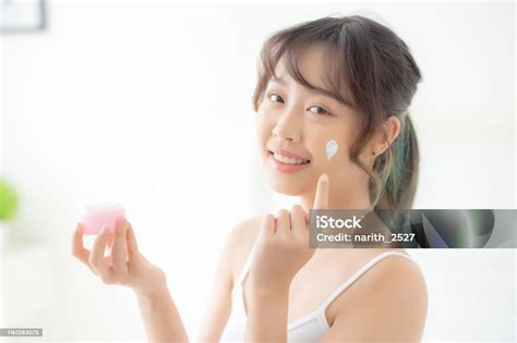 아름 다운 젊은 아시아 여자 행복 피부 얼굴에 보습제와 크림 또는 로션을 적용 미용 아시아 여자 적용 스킨 케어 터치 얼굴 화장품 메이크업 건강 하 고 웰빙 개념 보습제에