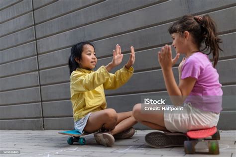도시 거리의 스케이트 보드에 앉아있는 친구와 함께 아시아 소녀 말하고 놀고 활동적인 라이프 스타일 키즈 개념 2명에 대한 스톡 사진 및 기타 이미지 Istock