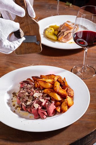 강판 트러플과 튀긴 감자를 곁들인 얇게 썬 고기와 와인 한 잔과 메인 코스가 테이블 위에 놓여 있습니다 감자 요리에 대한 스톡 사진 및 기타 이미지 Istock