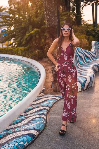 스트리트 스타일 적갈색 꽃 드레스와 도시 분수에서 황금 시간에 여름을 즐기는 현대 흰색 선글라스를 입은 젊은 갈색 머리 20 24세에 대한 스톡 사진 및 기타 이미지