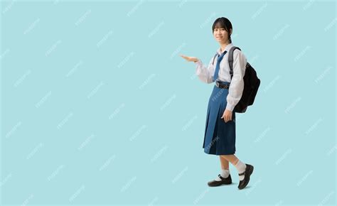디자인 작업을 위한 클리핑 패스가 있는 파란색 배경에 격리된 빈 공간을 손에 들고 손바닥을 들고 배낭을 메고 있는 전신 아시아