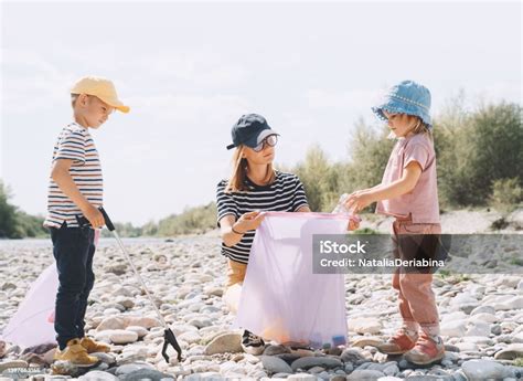 자원 봉사자 가족은 강 해변에서 플라스틱 쓰레기를 수거합니다 사람들은 자연을 깨끗하게 유지하고 쓰레기를 줍는 데 도움을줍니다 쓰레기에서 야외 공간을 청소하는 데 도움이되는