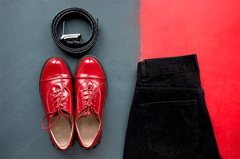 세련 된 여성의 옷 세련된 블랙 가죽 벨트 세련된 레드 페이턴트 가죽 신발과 회색과 빨간색 배경에 클래식 블랙 청바지의 세트 맨 위 보기 0명에 대한 스톡 사진 및 기타