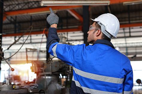 보호복을 입고 서서 워키토키 라디오를 사용하는 후방 기술자 엔지니어가 중공업 제조 공장에서 선반 금속 기계를 제어하거나 유지 보수 작업을 하는 동안 25 29세에 대한 스톡