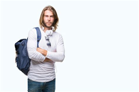 긴 머리 입고 젊은 잘생긴 관광 남자 교차 팔과 얼굴에 고립 된 배경 의심과 긴장 Disapproving 식 배낭 부정적인