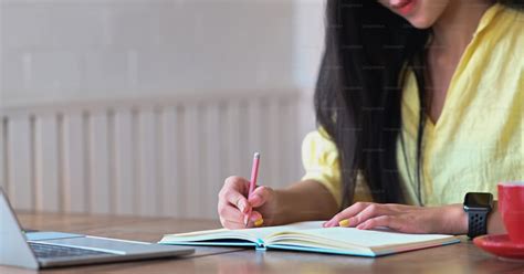 젊은 여성은 나무 작업 책상에서 컴퓨터 노트북 앞에 앉아 메모를 하고 있습니다 사진 Unsplash의 태국 이미지