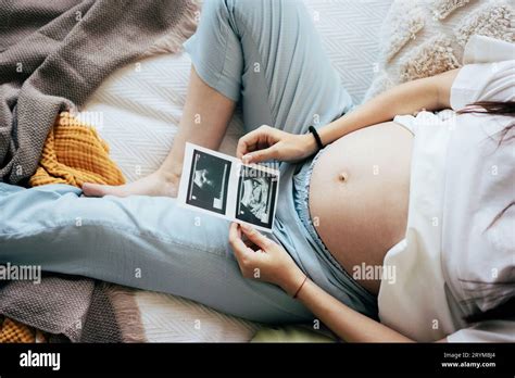 Unrecognizable Pregnant Woman In Third Trimester Lying On Bed Looking