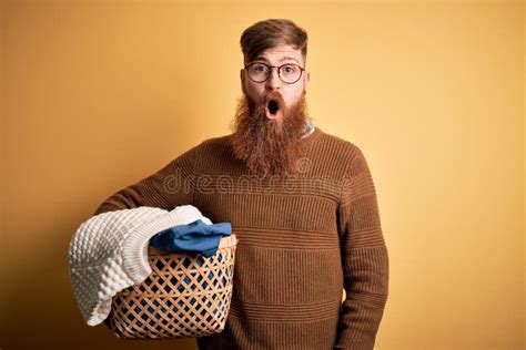 Redhead Irish Man With Beard Doing Housework Laundry Over Yellow