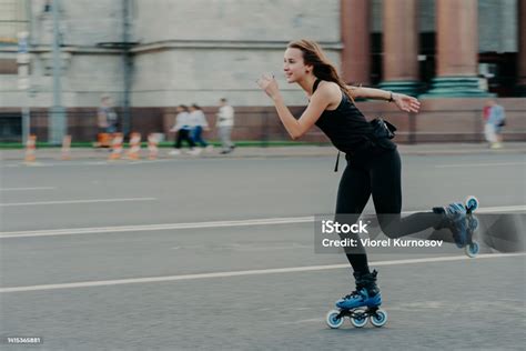 휴일과 활동적인 라이프 스타일 컨셉 슬림 한 건강한 유럽 여성 롤러 스케이트 고속 포토 가페드 모션에 검은 옷을 입고 도로에 흐린 거리 배경에 포즈 20 24세에 대한 스톡
