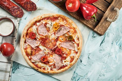 토마토 치즈 햄 레드 소스를 곁들인 홈메이드 오븐에서 구운 고기 피자 바삭바삭한 피자 밝은 배경에 토마토와 구성 공간을 복사합니다 맨 위 보기 0명에 대한 스톡 사진 및