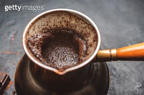 Fresh brewed coffee in the turkish jezva coffee pot on dark background ...
