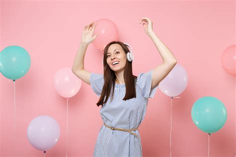 파란 드레스 듣기 음악 화려한 공기 풍선 파스텔 핑크 배경에 춤 헤드폰 행복 한 예쁜 젊은 여자의 초상화 생일 휴가 파티 사람들이 진심으 감정 개념 14에 대한 스톡 사진