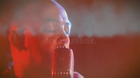 Man Singing Into Retro Microphone On Music Stage Amid Red Haze