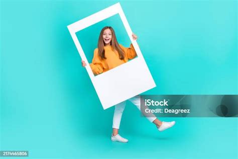 예쁜 흥분 여학생이 오렌지 스웨트 셔츠를 입고 종이 사진 프레임을 들고 절연 된 청록색 배경의 전체 길이 사진 12 13세에 대한 스톡 사진 및 기타 이미지 Istock