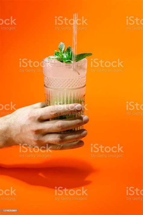 복사 공간이 있는 주황색 배경에 열대 모히토 칵테일 한 잔을 들고 있는 한 남자의 손을 닫습니다 여름 방학 개념입니다 감귤류 과일에 대한 스톡 사진 및 기타 이미지 Istock