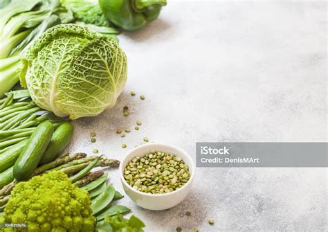 모듬된 그린 톤의 흰색 돌 배경에 원시 유기농 야채 아보카도 양배추 브로콜리 콜리플라워와 트림된 콩 및 분할 완두콩 흰 그릇에 오이 텍스트를 위한 공간 0명에 대한 스톡