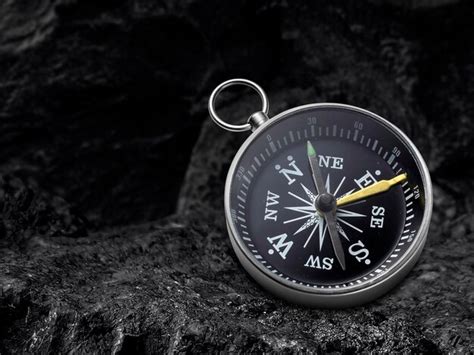Premium Photo Compass Nestled On Black Coal Background Travel Destination And Navigation Concept
