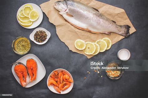 생선 흰 접시 레몬 후추와 소금에 연어 새우의 레몬 조각으로 갈색 공예 종이 어두운 회색 테이블에 배치 됩니다 건강한 생활방식에