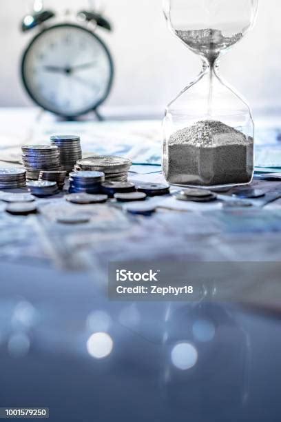 국제 통화의 동전 지폐와 테이블에 모래 시계 모양을 통해 실행 하는 은색 모래 시간을 투자 하 고 은퇴 절약입니다 비즈니스 마감 개념에 대 한 긴급 카운트 다운 타이머