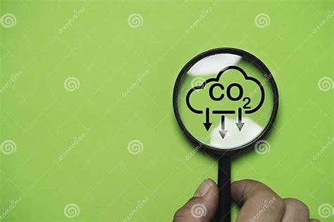 Hand Holding Co2 Reducing Icon Inside Magnifier Glass For Focusing