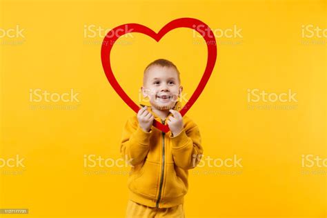 리틀 아이 보가 34 년 된 노란색 옷을 입고 오렌지 벽 배경 어린이 스튜디오 초상화에 고립 된 붉은 마음 잡으십시오 사람들이