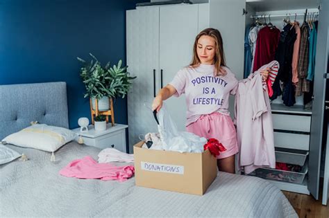 자선 상점에 기부하기 위해 옷장에서 엄선 된 옷을 입는 여성 정리 옷 정리 및 청소 재사용 중고 개념 의식있는 소비자 지속 가능한 라이프 스타일 의류에 대한 스톡 사진 및