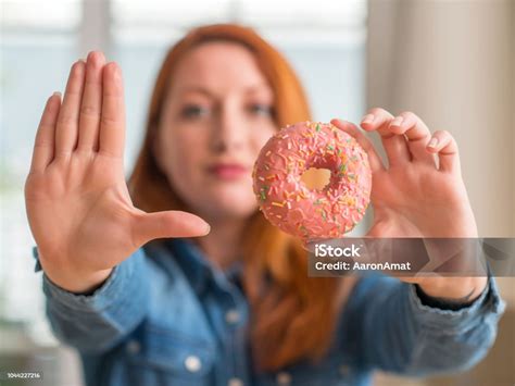 빨간 머리 여 자가 심각 하 고 자신감 표현 방어 제스처 정지 표시를 하 고 오픈 손으로 도넛 집에서 들고 건강에 좋지 않은