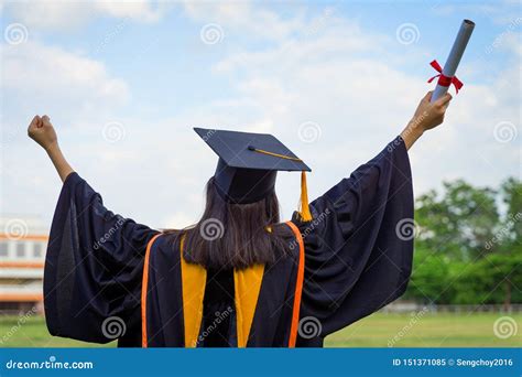 Rear View Of A Female University Graduate Stands And Holds Degree Certificate To Celebrate In