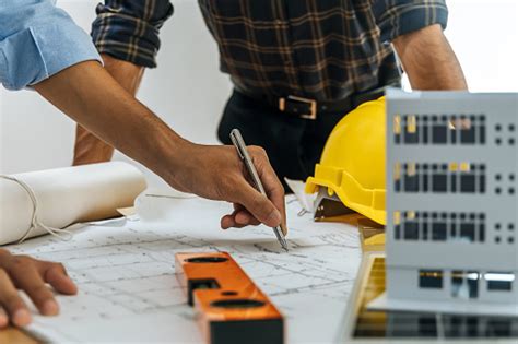 엔지니어링 건축가 또는 인테리어 디자이너는 건설 현장 계약자 건축 산업 엔지니어 개념의 회의실 사무실에서 책상 위의 청사진을 계산 계획 및 작업합니다 2명에 대한 스톡 사진