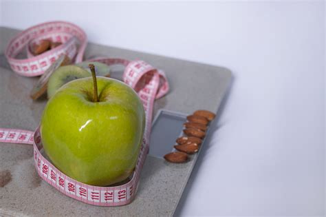 베이지 색 욕실 비늘에 빨간 측정 테이프 사과 키위와 아몬드 다이어트와 건강한 삶 체중 감량 스포츠 컨셉 맨 위 보기입니다 공간을 복사합니다 격리 흰색 배경 사과에 대한