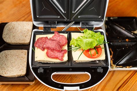 토마토 햄 양파 및 치즈를 곁들인 두 가지 샌드위치가있는 샌드위치 메이커 가벼운 식사 준비 건강한 식생활에 대한 스톡 사진 및