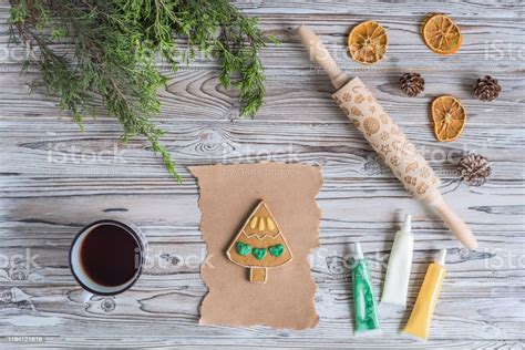 나무 회색 테이블과 공예 용지에 크리스마스 트리의 형태로 꿀 진저 브레드 쿠키를 장식하는 여성 빈 비스킷 진저 브레드 작은