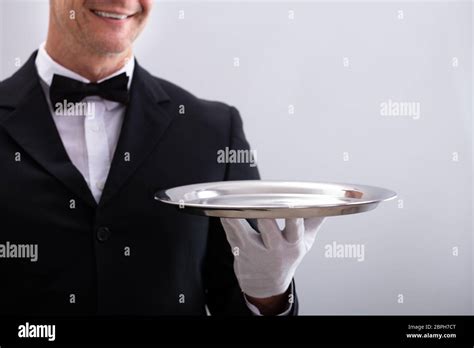 Close Up Of Waiters Hand Holding Empty Silver Tray Against White