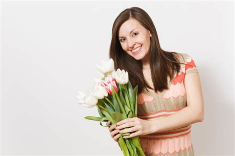 빛 꽃무늬 드레스에 매력적인 젊은 웃는 갈색 머리 여자 손 흰색과 분홍색 튤립 꽃다발에 들고는 웃 고 기 뻐에 고립 된 흰색 배경 휴가 좋은 분위기의 개념입니다 꽃 나무에