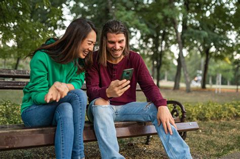 공공 공원에서 스마트 폰을 사용하여 비디오를 보면서 즐거운 시간을 보내는 두 친구 2명에 대한 스톡 사진 및 기타 이미지 2명 30 34세 Brand Name