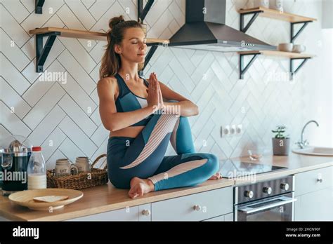 Fit Concentrated Caucasian Woman Sitting On Talbe In Kitchen And