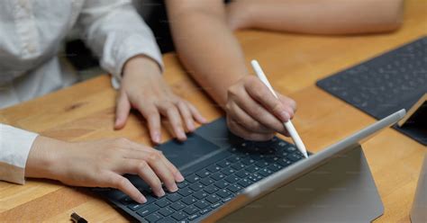 나무 테이블에서 모형 태블릿으로 작업하는 동안 프로젝트에 대해 논의하는 두 명의 여성 작업자의 클로즈업 보기 사진 Unsplash의 인간의 손 이미지