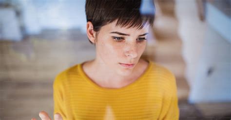 집에서 실내에 서 있는 슬픈 젊은 여성의 전면 모습 창문에 손을 얹다 유리를 통해 촬영했습니다 사진 Unsplash의 의류 이미지