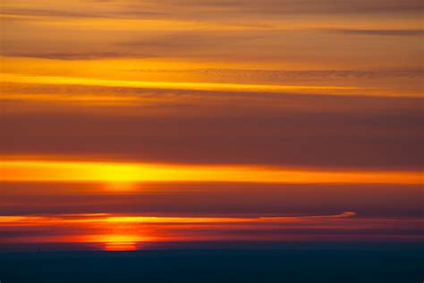 큰 붉은 태양 원 따뜻한 색조의 배경 수조의 구름에 어두운 수평선 뒤에서 밖으로 상승 한다 아름 다운 구름 하늘에 새벽의 아름 다운 배경입니다 0명에 대한 스톡 사진 및